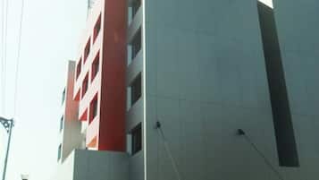 Um hotel com uma placa grande e marcante em vermelho e branco, design arquitetônico moderno e um aviso indicando um evento para crianças.