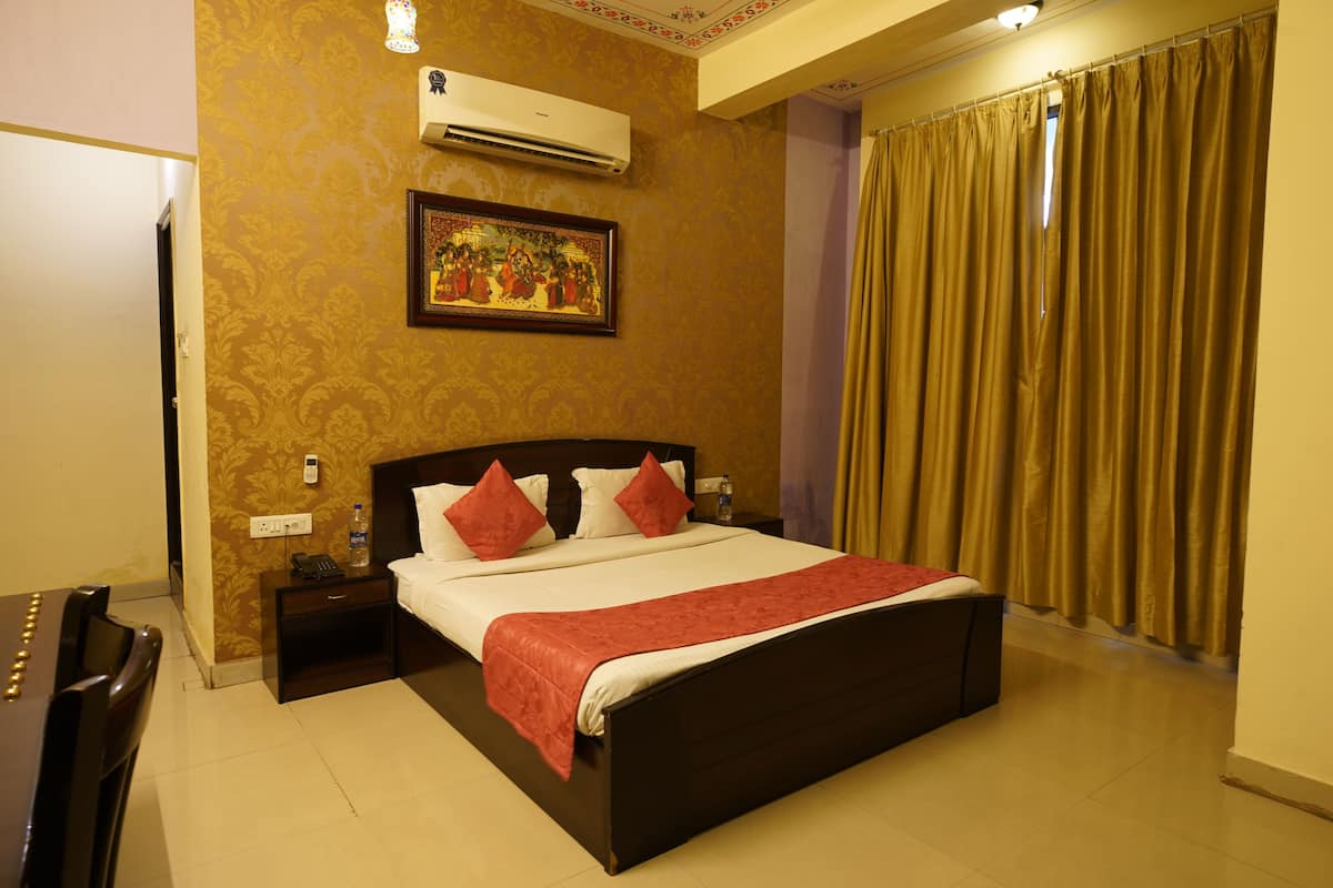 Quarto de hotel com uma cama grande, uma mesa de cabeceira, uma escrivaninha e ar condicionado fixado na parede.
