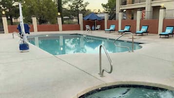 Piscina com espreguiçadeiras e área de hidromassagem.