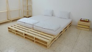 Quarto minimalista com estrutura de cama de madeira, roupa de cama branca e uma pequena mesa de cabeceira de madeira.
