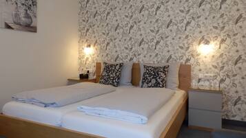Quarto com cama, mesas de cabeceira e parede decorada com papel de parede floral.