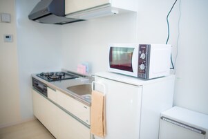 Uma cozinha compacta com fogão a gás, micro-ondas e um pequeno frigorífico.