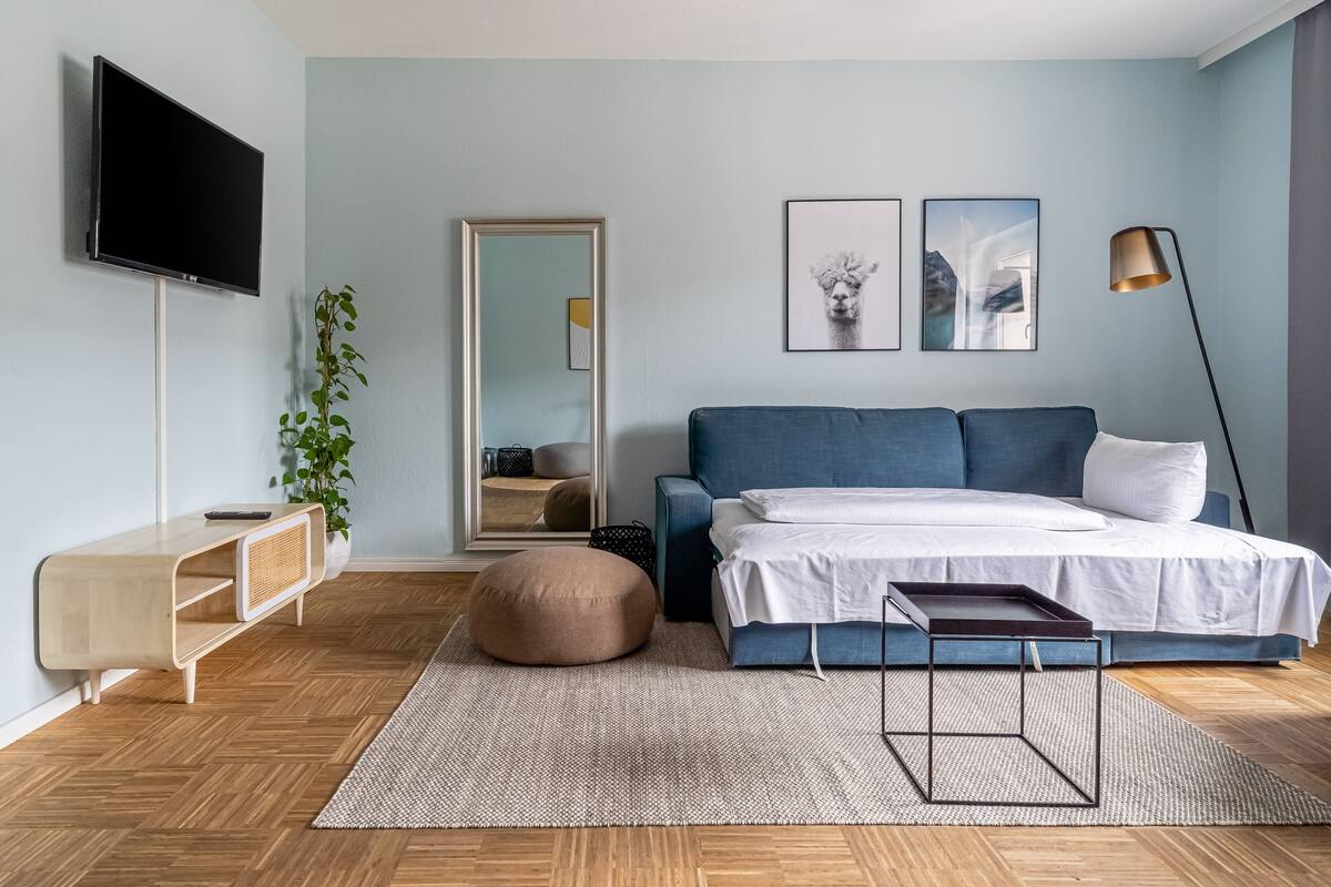 Quarto moderno com cama, mesa de cabeceira, abajur e obra de arte.