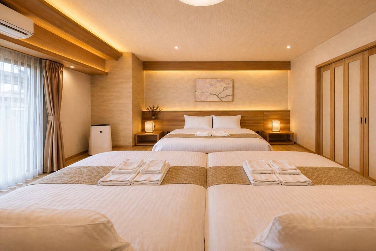 Quarto de hotel com duas camas, teto de madeira, uma obra de arte pendurada na parede e mesa de cabeceira com abajur.