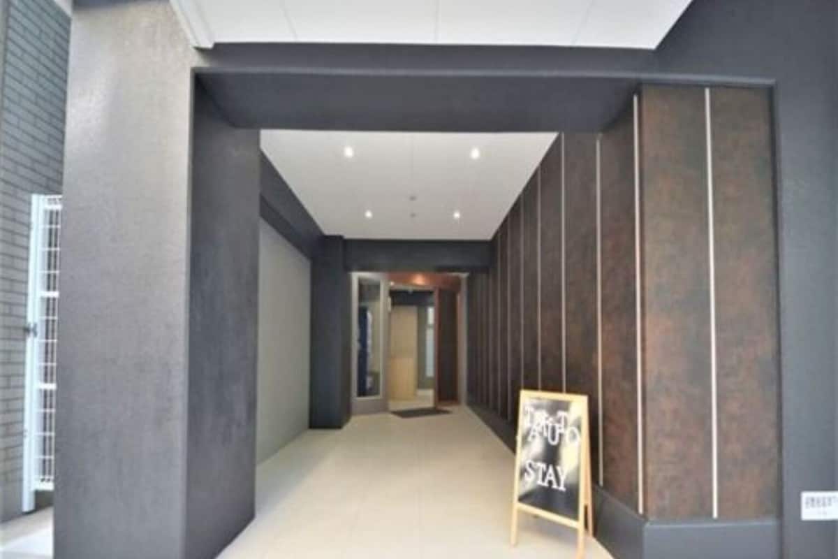 Um corredor com uma placa, uma porta e piso ladrilhado.