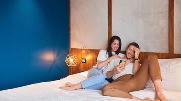 Quarto com cama, mesa de cabeceira e luminária na parede.