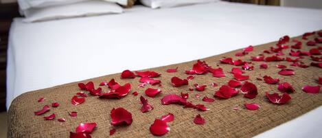 Uma cama com um cobre-leito marrom e pétalas de rosa espalhadas.