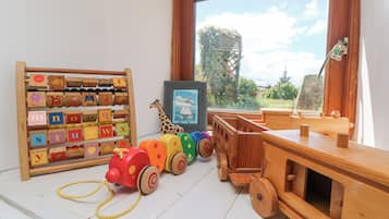 Um conjunto de brinquedos de trem de madeira sobre uma prateleira branca, um suporte de blocos de alfabeto de madeira e uma moldura com uma foto de um farol.