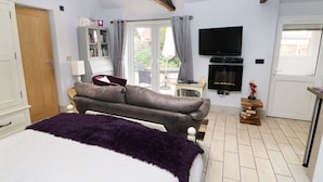 Quarto com cama, televisão, lareira e janela com cortinas.