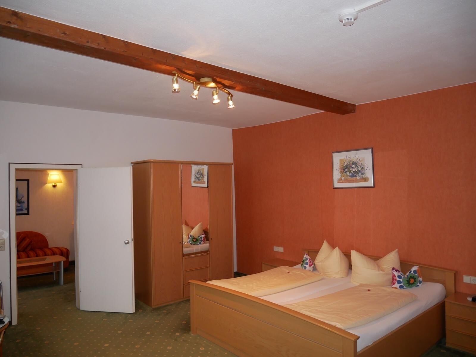 Quarto com cama de madeira, mesa de cabeceira, guarda-roupa e luminária no teto.
