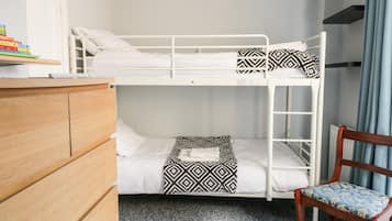 Quarto com beliche, cômoda de madeira, uma cadeira e uma estante de livros.