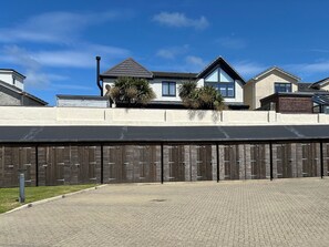 Uma área residencial com calçada pavimentada, uma fileira de portões de madeira e casas com estilos arquitetônicos distintos.