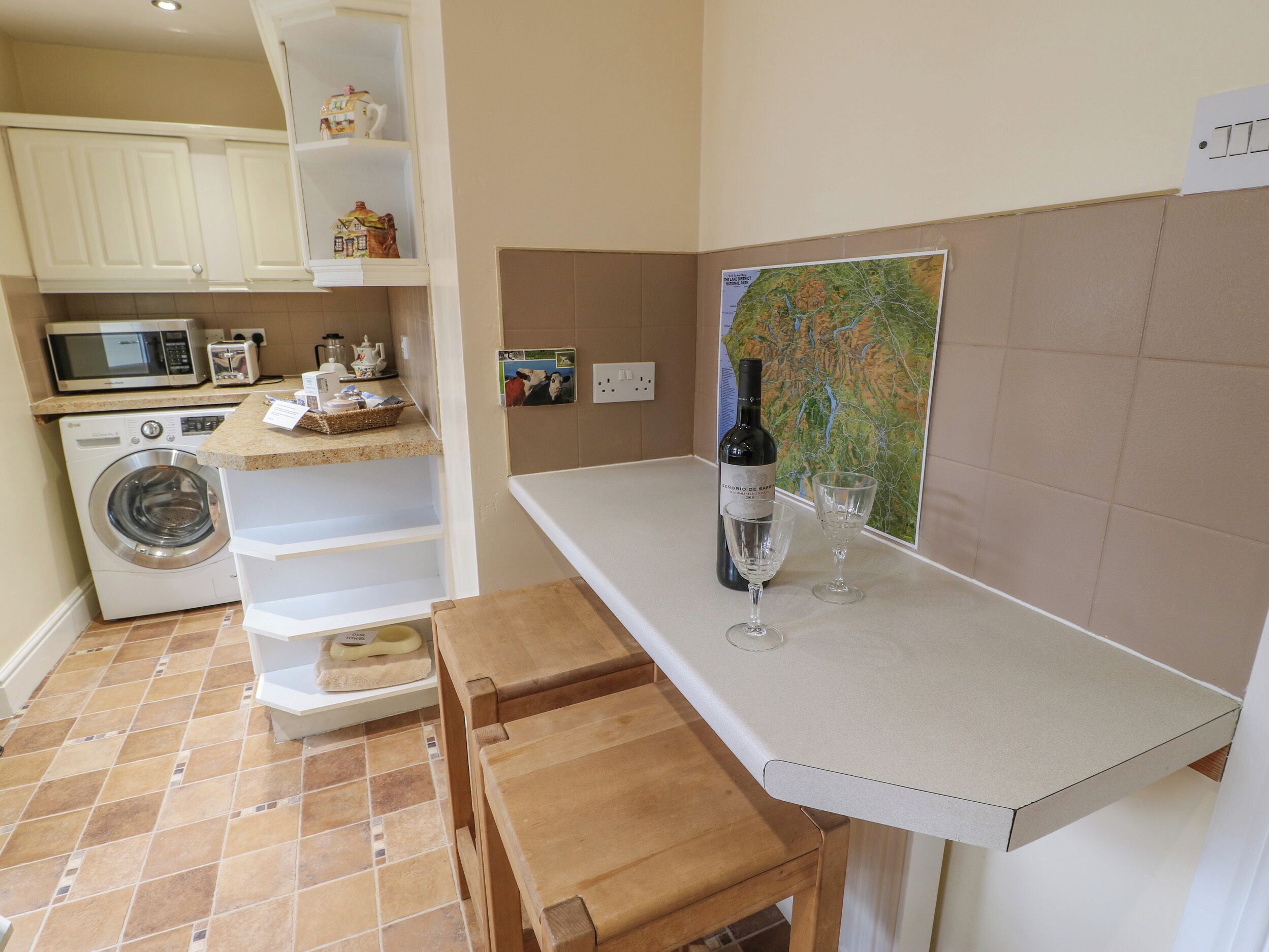Uma cozinha compacta com máquina de lavar, micro-ondas e um mapa na parede.