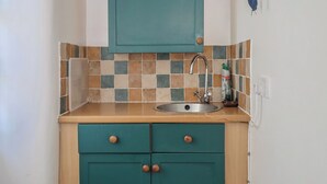 Cozinha compacta com armários verde-água, pia de aço inoxidável e painel de azulejos.