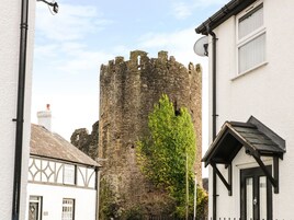 Uma torre de pedra histórica com um edifício branco em primeiro plano.