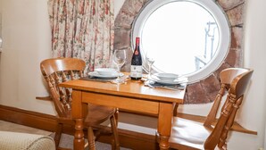 Uma mesa de jantar de madeira com cadeiras, uma garrafa de vinho e um copo.