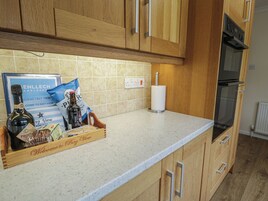 Uma cozinha com armários de madeira, bancada e painel de azulejos.