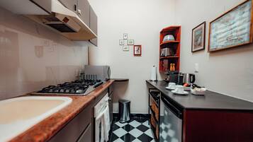Uma cozinha compacta com fogão a gás, pia e máquina de café.