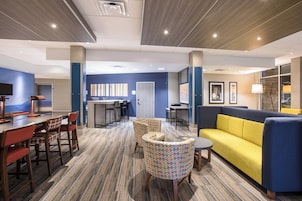 Um hall de hotel com bar, área de estar e balcão de recepção.