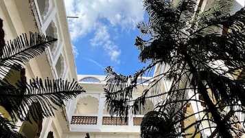 Um pátio com teto alto, paredes brancas e vista do céu pela abertura no telhado.