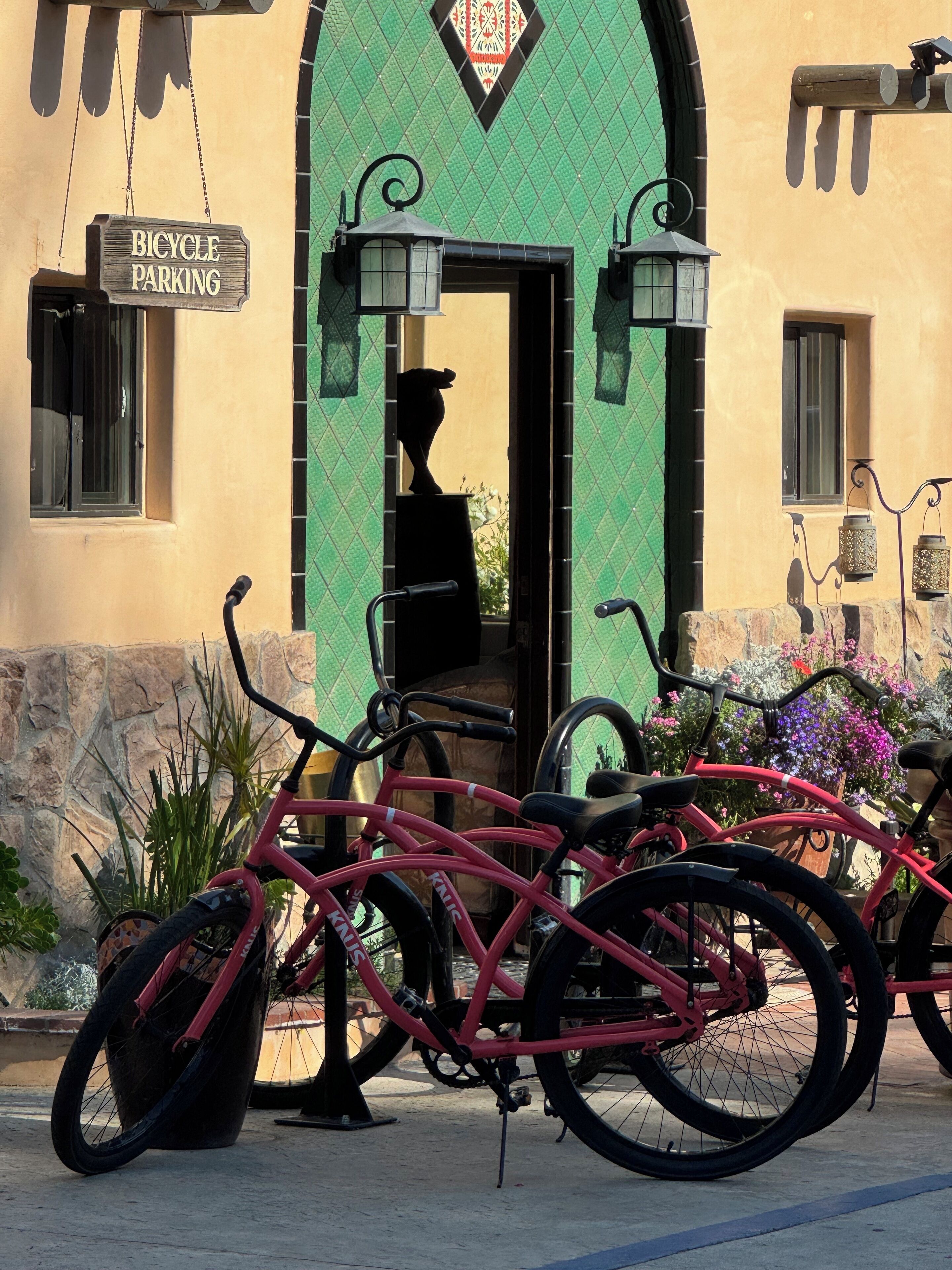 Uma bicicleta estacionada em frente a um edifício com placa indicando estacionamento para bicicletas.
