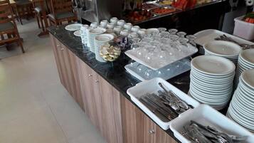 Uma mesa de buffet com pratos, tigelas e talheres.