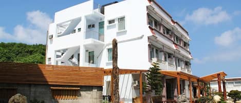 Um edifício moderno de dois andares com telhado plano, janelas amplas e área externa coberta para sentar.