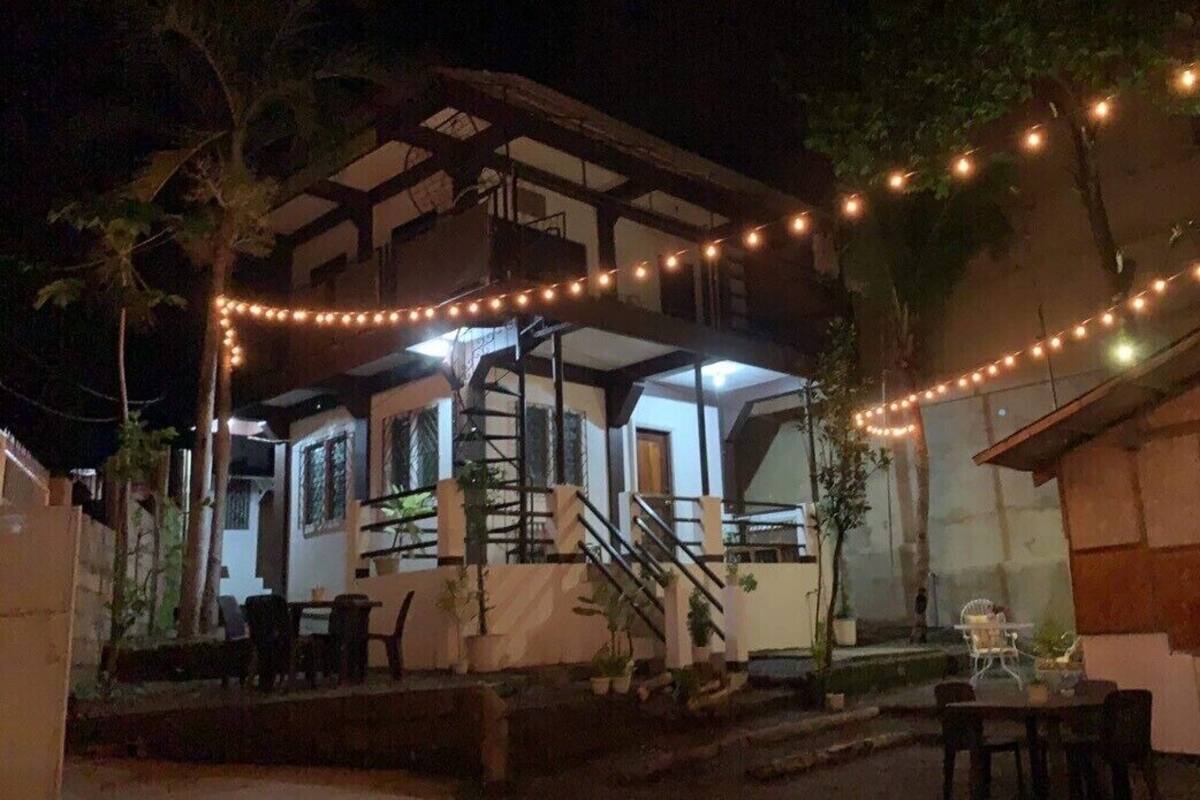 Um edifício de dois andares com escadaria e área de estar ao ar livre, decorado com luzes de Natal.