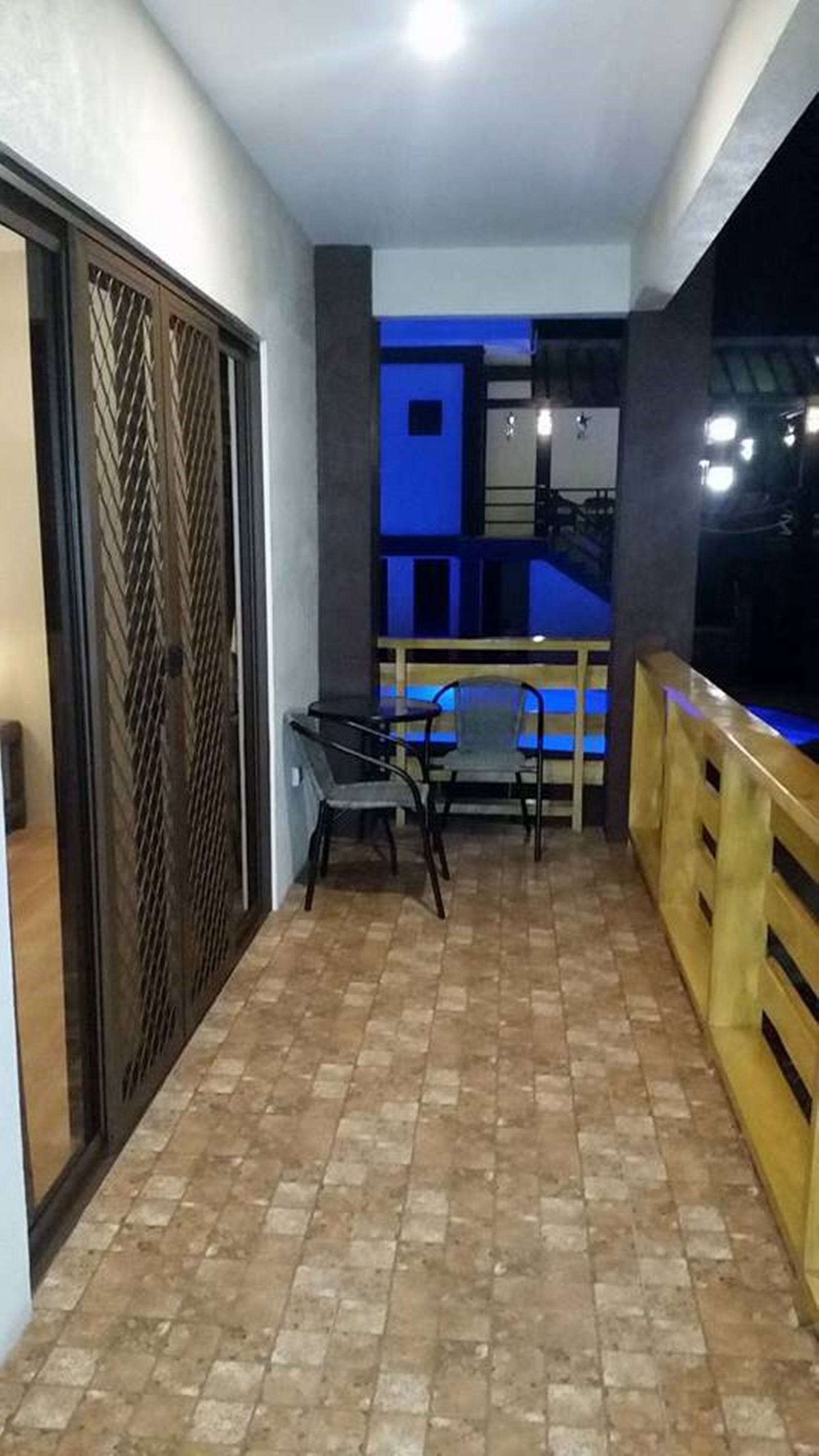 Uma varanda com piso de azulejos, uma mesa com cadeiras e um guarda-corpo.