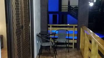 Uma varanda com piso de azulejos, uma mesa com cadeiras e um guarda-corpo.