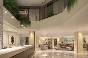 Um lobby moderno com balcão de recepção, área de estar e bar.