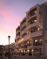 Um hotel com vários andares, varandas, entrada no nível do solo e área de estar ao ar livre.
