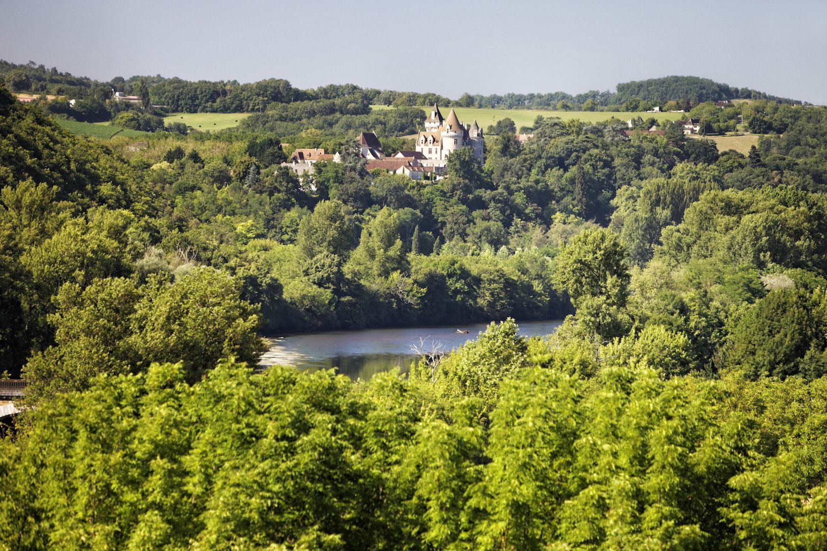 Um castelo rodeado por vegetação exuberante e um rio.