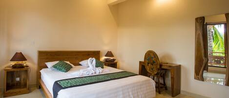 Um quarto espaçoso com uma cama grande, cabeceira de madeira e mesa de cabeceira de madeira com uma luminária.