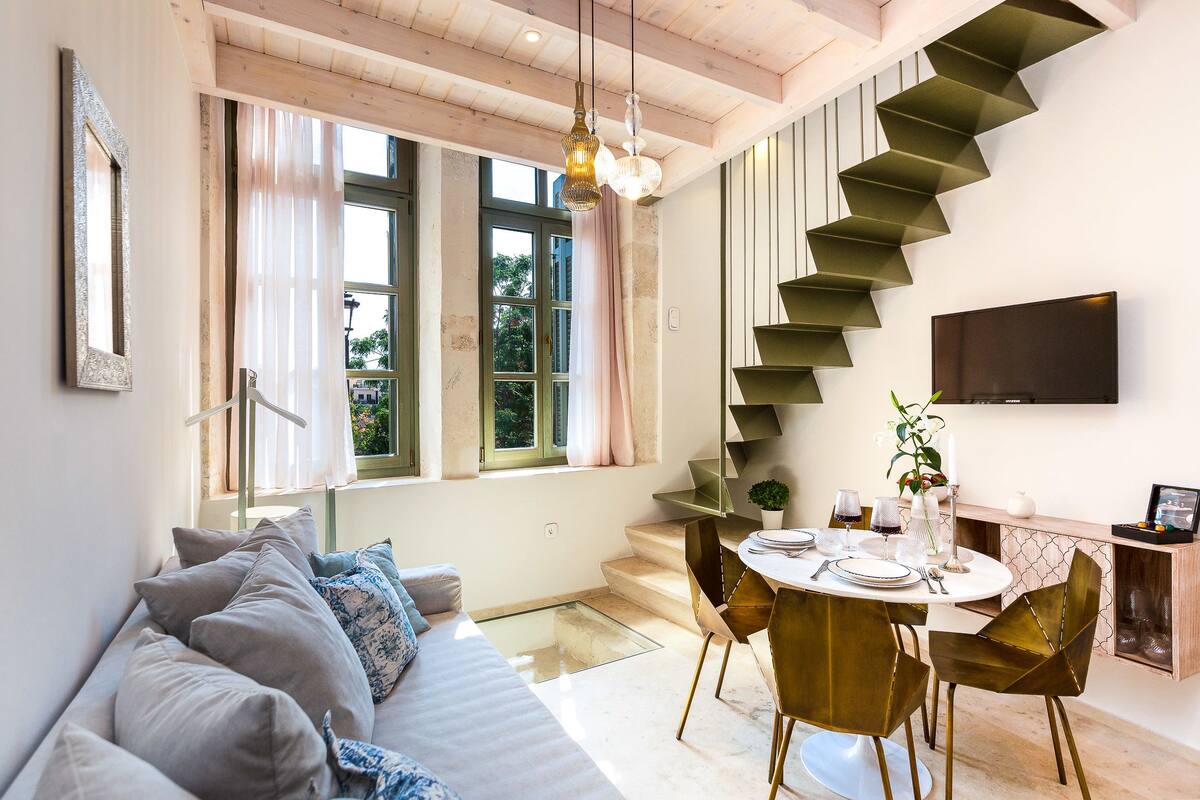 Uma sala de estar moderna com sofá, mesa de jantar e escada.