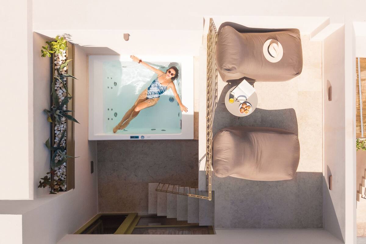 Uma área de spa moderna com uma banheira grande, um espaço de estar com um banco acolchoado e uma escada que leva a um andar superior.