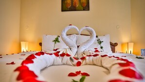 Cama com pétalas de rosa e toalhas dispostas em formato de coração.