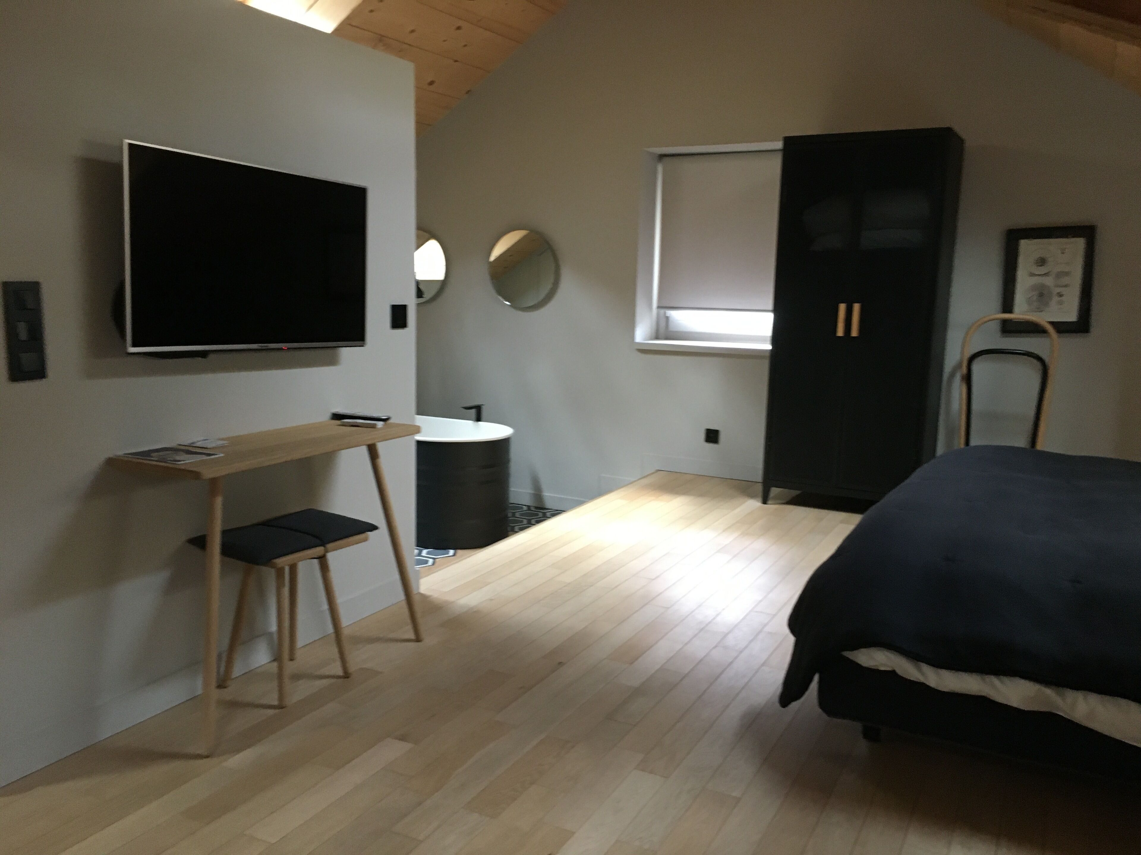 Quarto com cama, escrivaninha, televisão, janela e guarda-roupa.