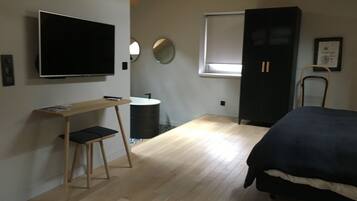 Quarto com cama, escrivaninha, televisão, janela e guarda-roupa.