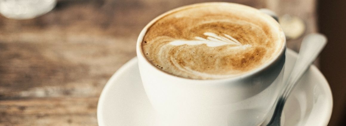 Uma chávena de café com arte de latte no pires.