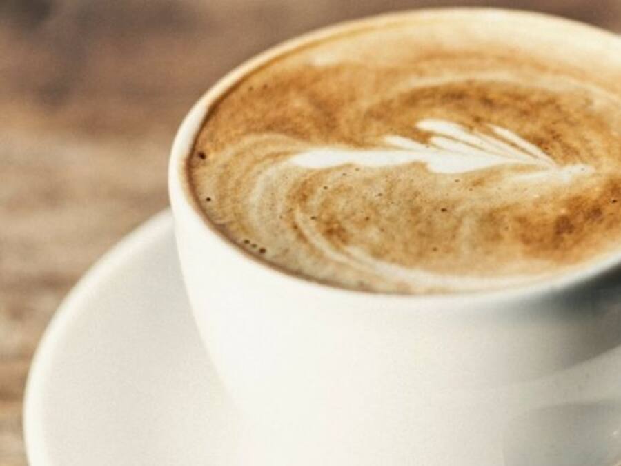 Uma chávena de café com arte de latte no pires.