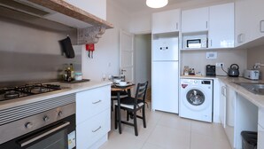 Uma cozinha compacta com fogão a gás, micro-ondas e máquina de lavar integrada.