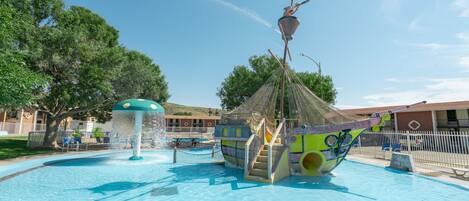 Um parque aquático com uma estrutura de recreação colorida, uma fonte de água e uma piscina.