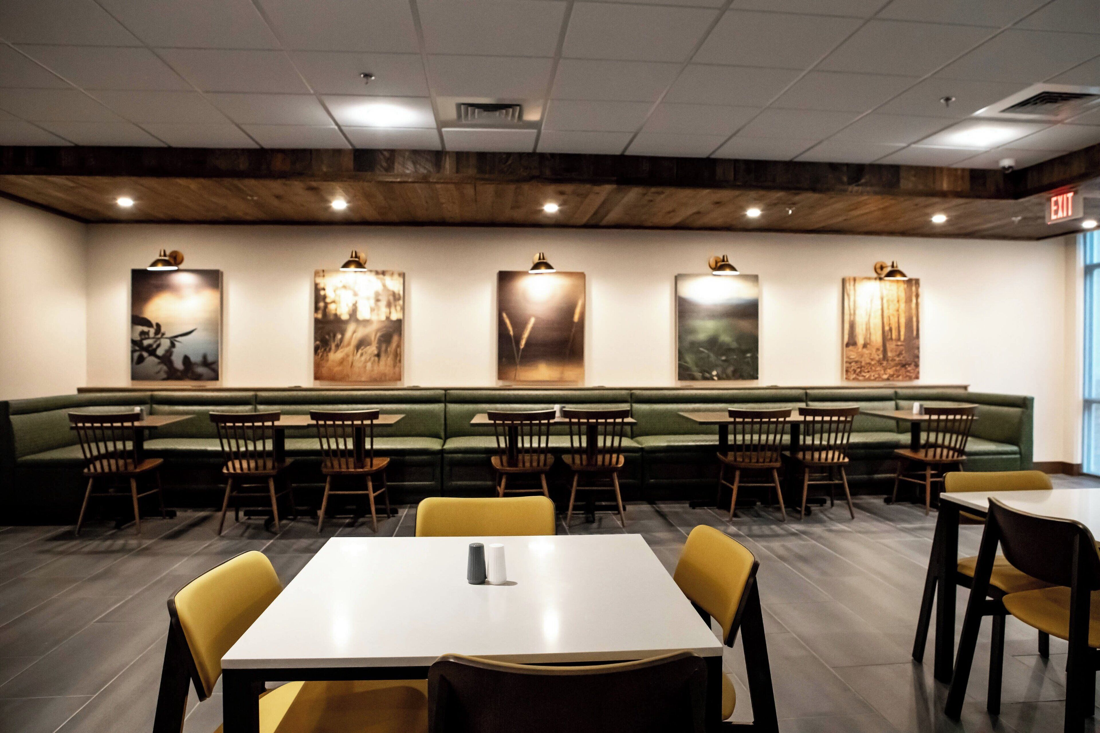 Um restaurante com um amplo banco verde, várias mesas e cadeiras.