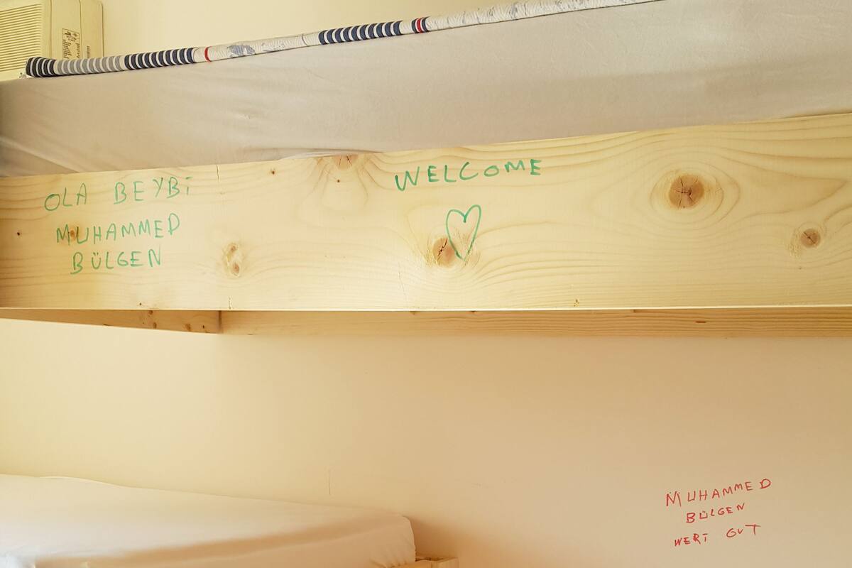 Uma cama beliche com cabeceira de madeira e colchão com manta listrada.