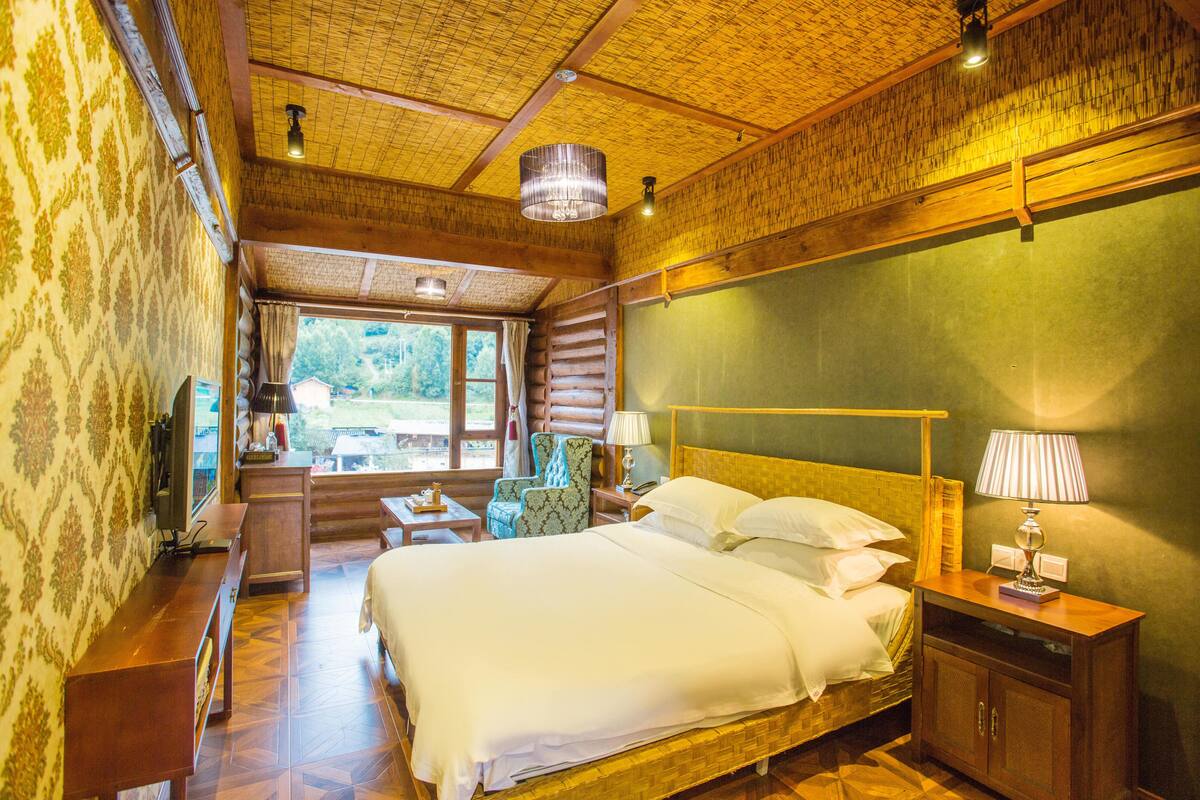 Quarto espaçoso com uma cama grande, cabeceira de madeira e vista para o exterior.