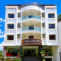 Um hotel de vários andares com uma placa chamativa para 'SAPA LAND HOTEL' no nível da rua.