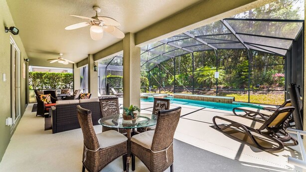 Uma área de varanda coberta com piscina, móveis de exterior e um bar.