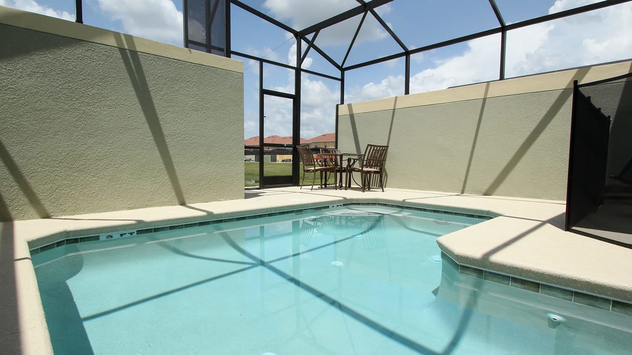 Piscina interna com teto de vidro, rodeada por paredes bege e cadeiras de madeira.