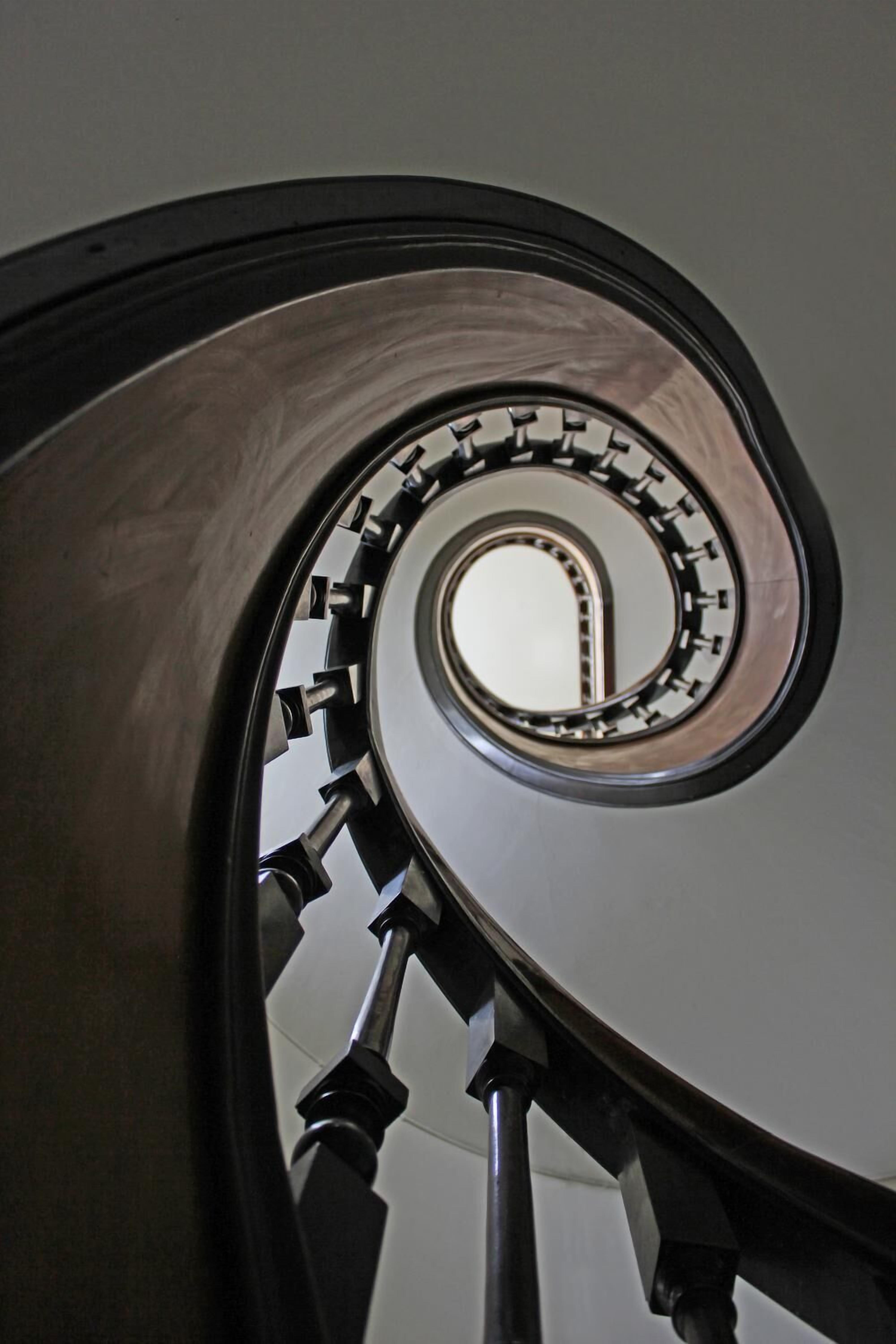 Uma escadaria em espiral com corrimão metálico e um desenho circular central.